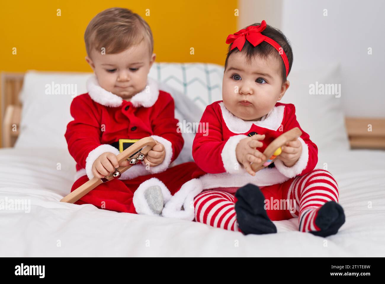 Adorable boy and girl wearing christmas clothes holding rattle at ...