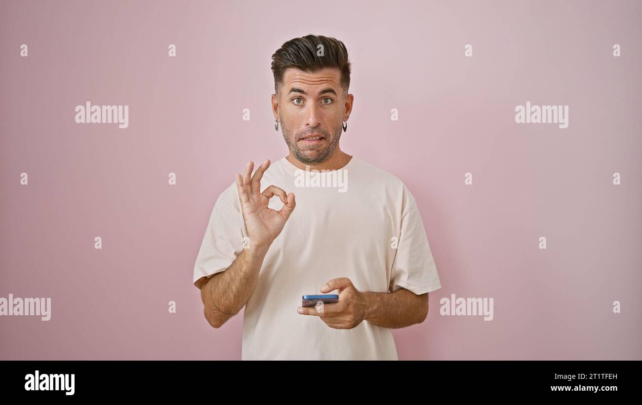 Young, attractive hispanic guy, casually standing over pink isolated ...