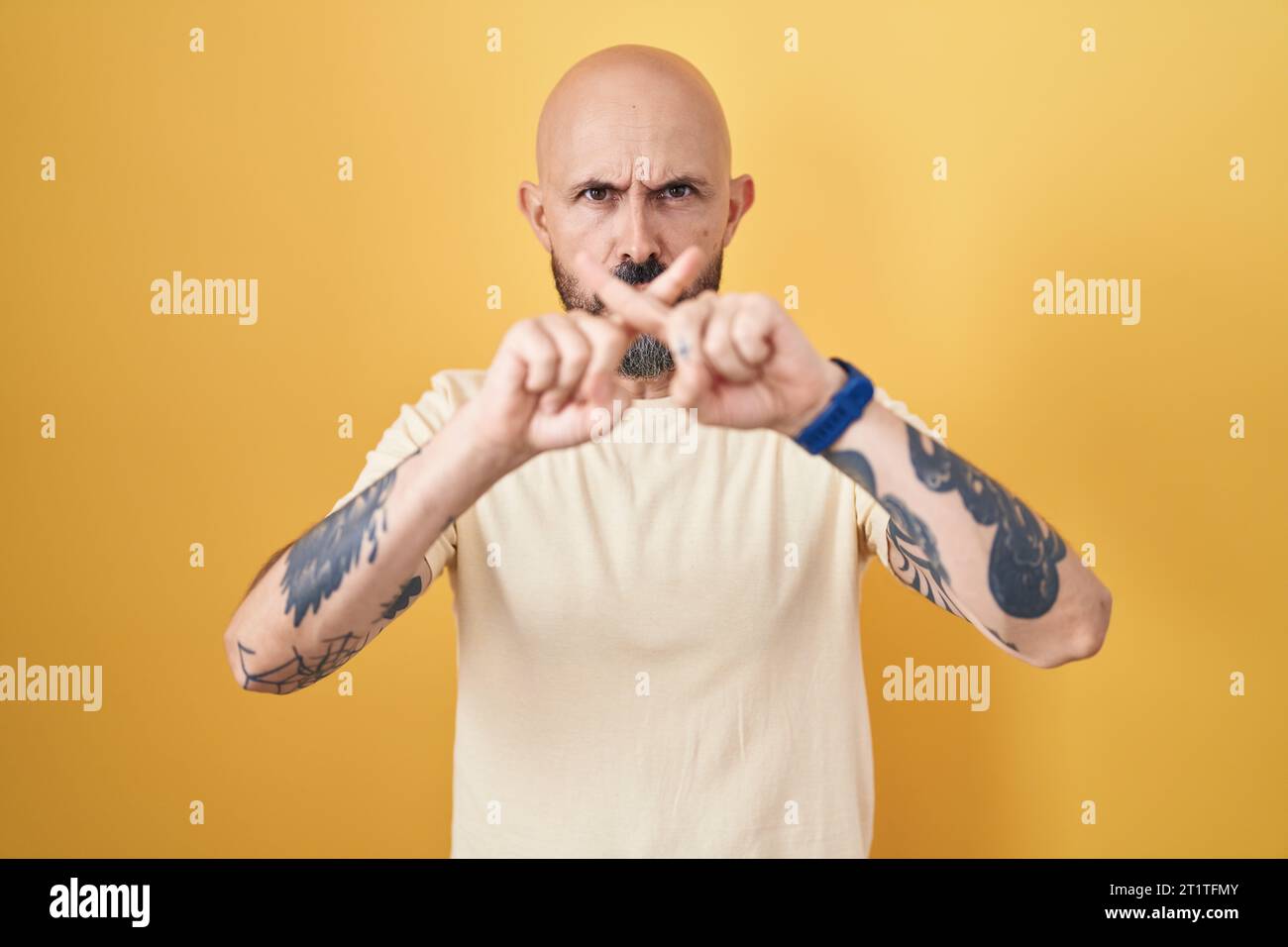 Hispanic man with tattoos standing over yellow background rejection ...