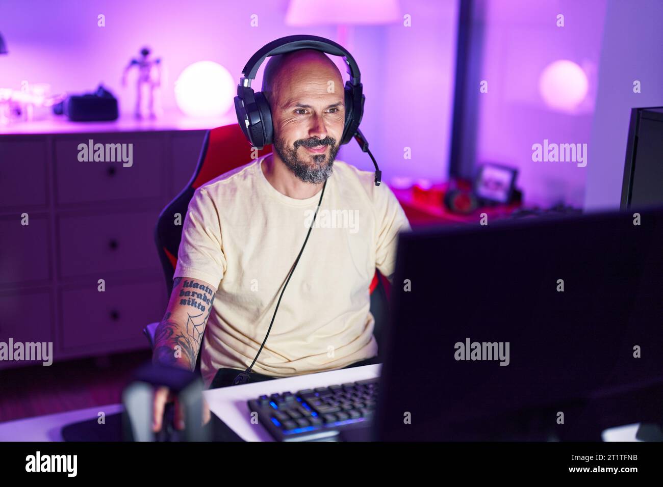 Young bald man streamer playing video game using computer at gaming ...