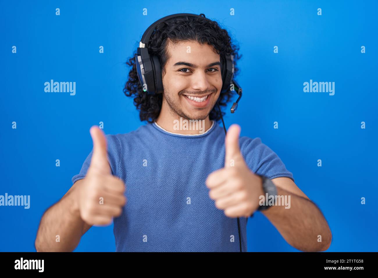 Hispanic man with curly hair listening to music using headphones ...