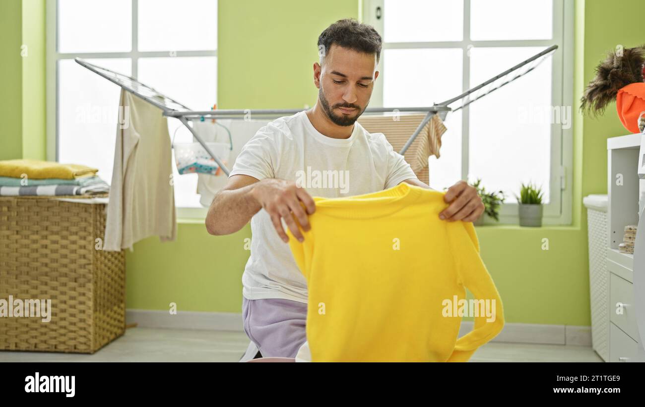 Young arab man folding clothes at laundry room Stock Photo - Alamy