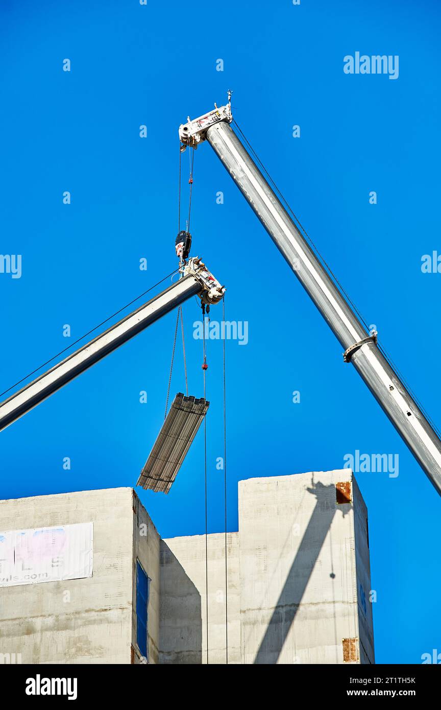 Cranes lifting building materials on to site Stock Photo - Alamy