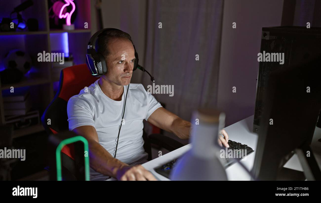 Handsome middle age man streaming video game at night, sitting ...