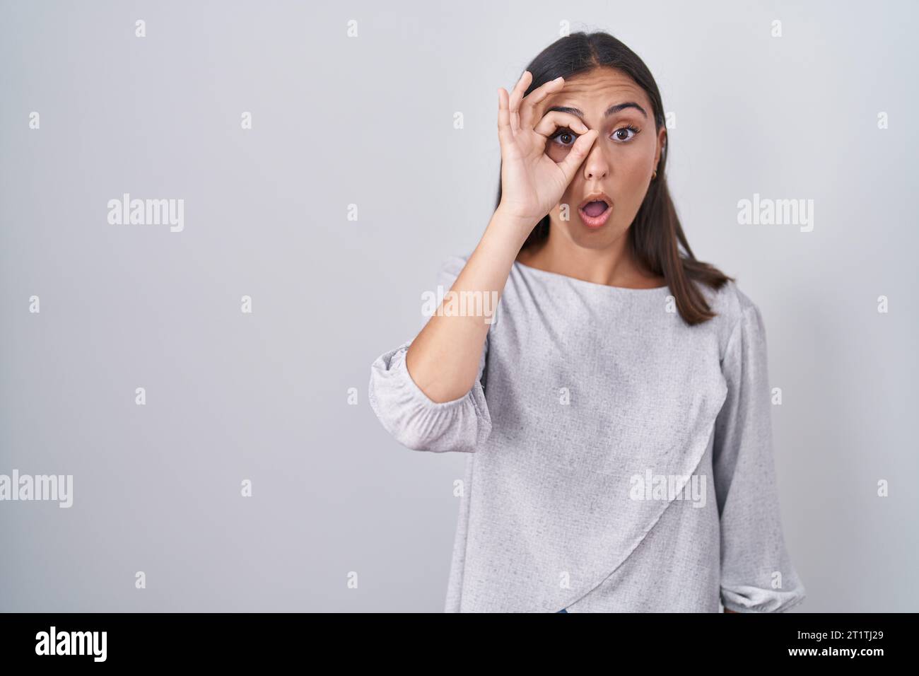 Young hispanic woman standing over white background doing ok gesture ...
