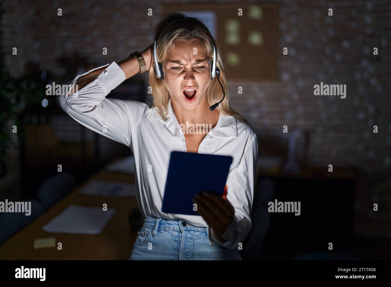 Young blonde woman working at the office at night crazy and scared with ...