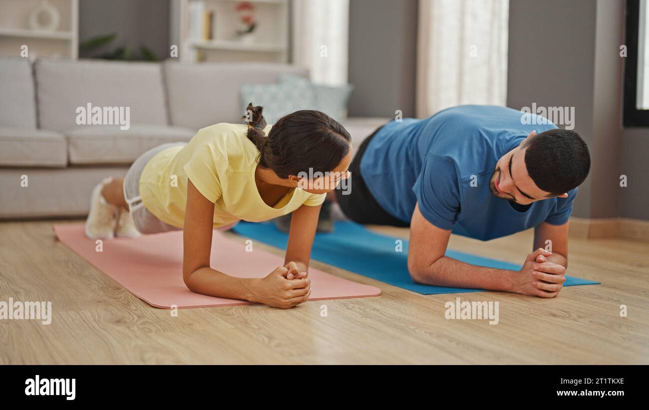 Beautiful couple at home, all smiles as they exercise together training ...