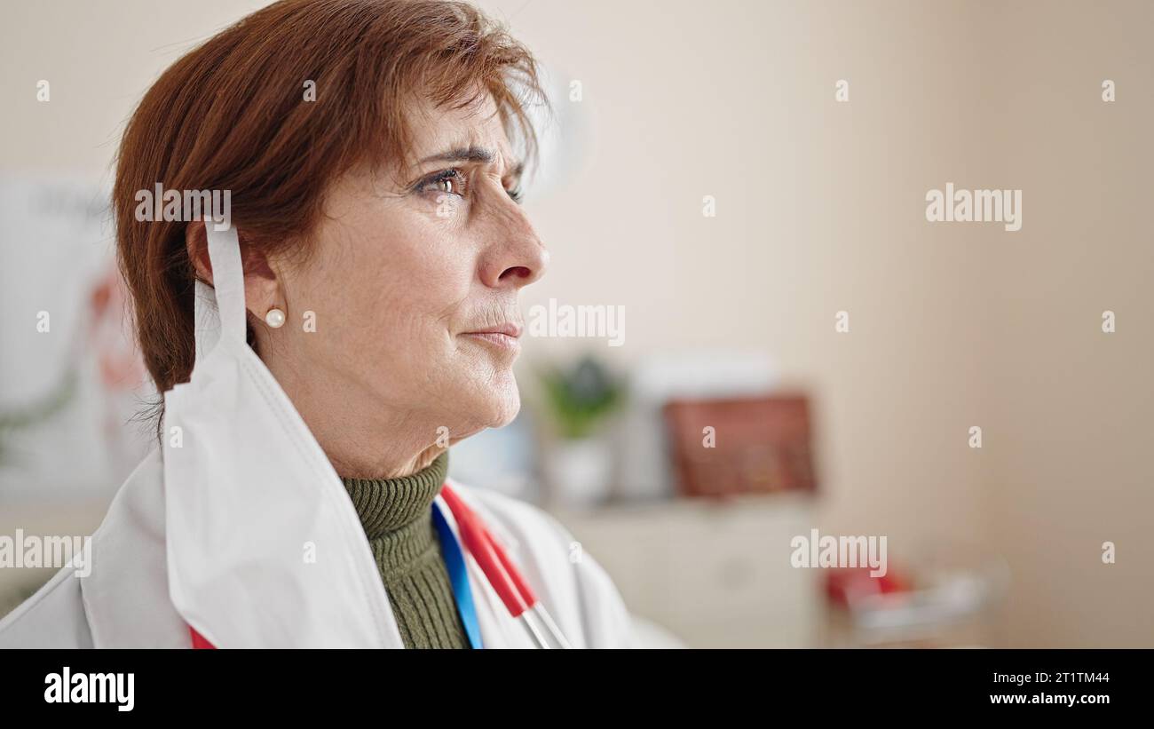 Mature hispanic woman doctor standing with serious expression wearing ...