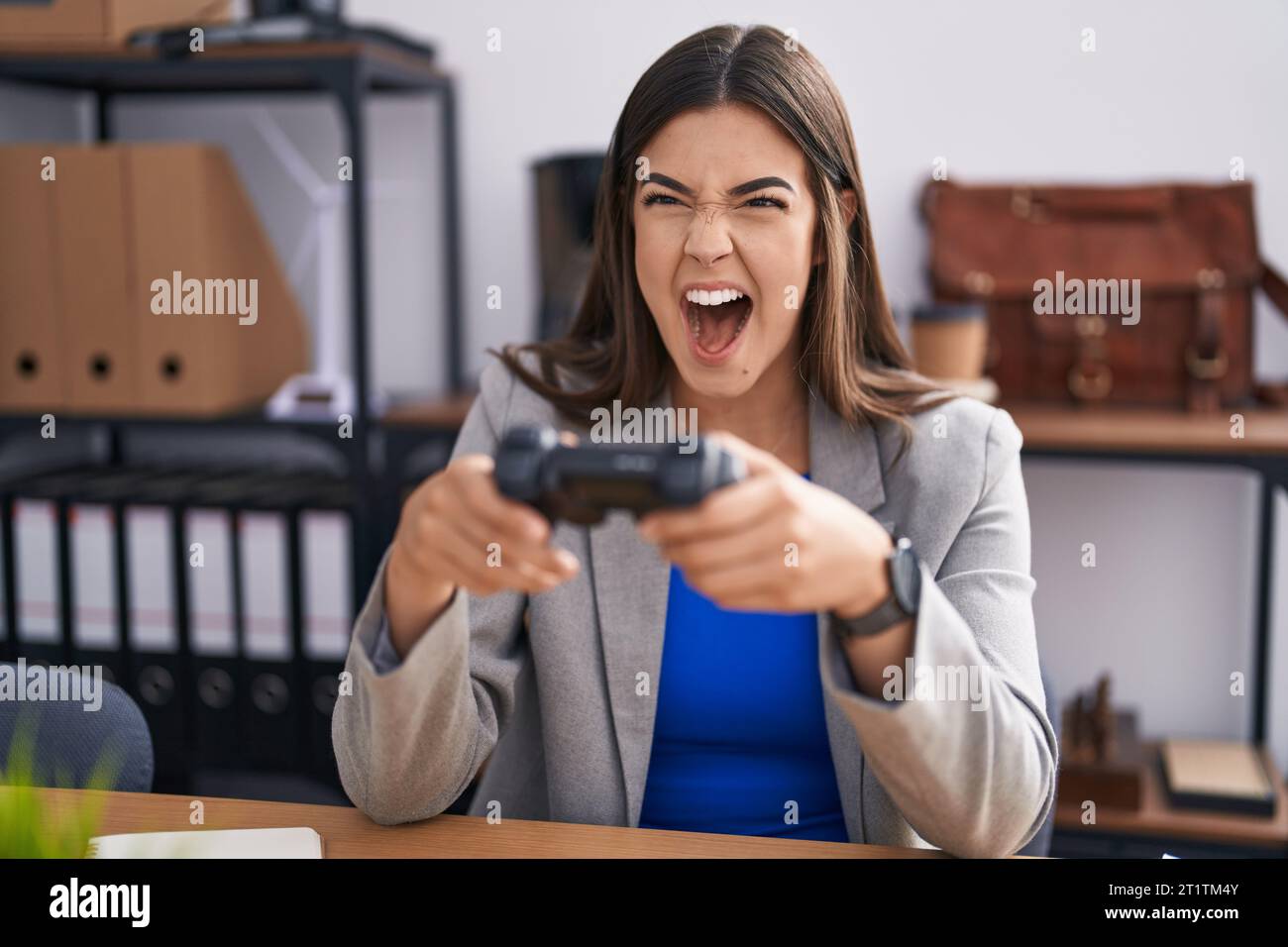 Hispanic woman working at the office playing video games angry and mad ...