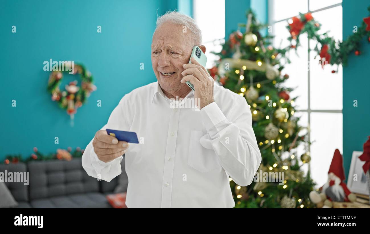 Senior grey-haired man angry talking on smartphone holding credit card ...