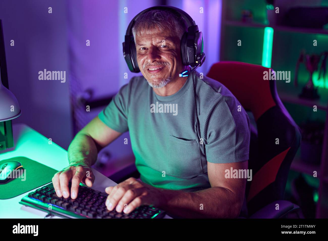 Middle age grey-haired man streamer playing video game using computer ...