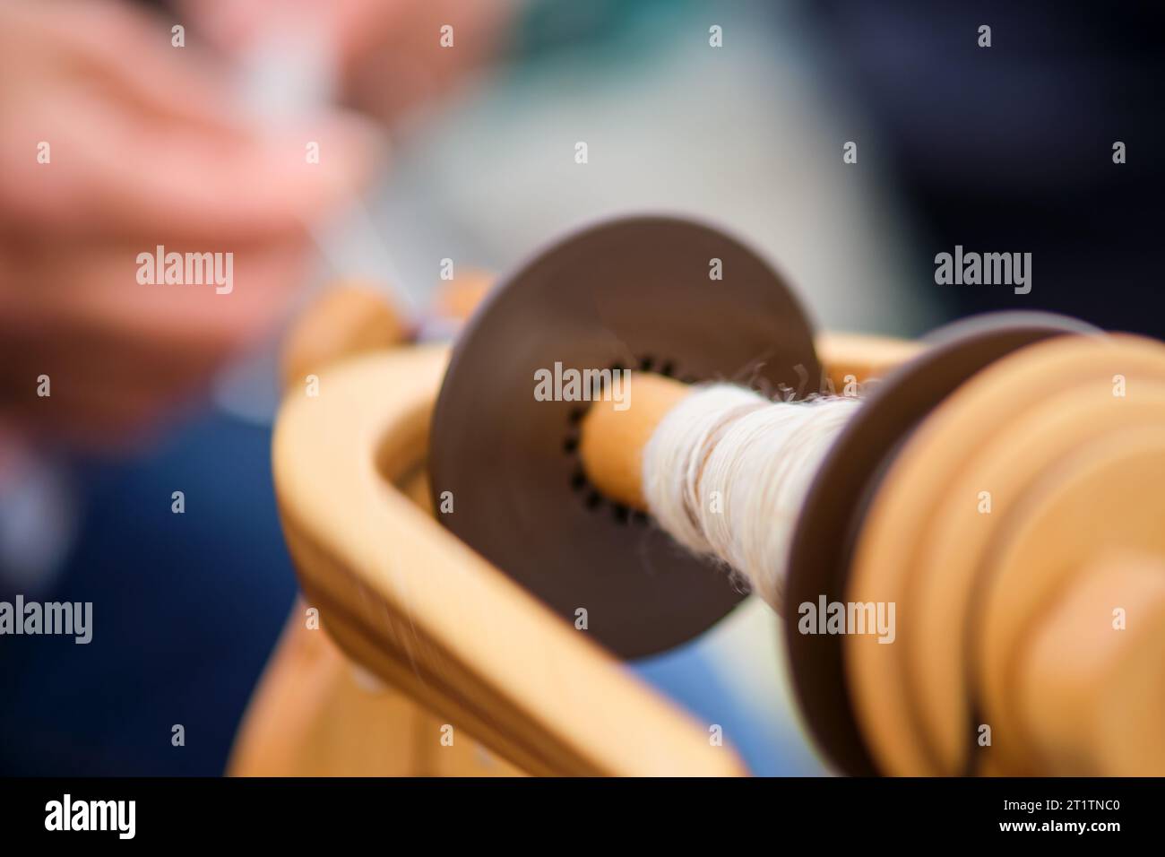 The closeup shot shows a hand spinning thread on a vintage spinning ...