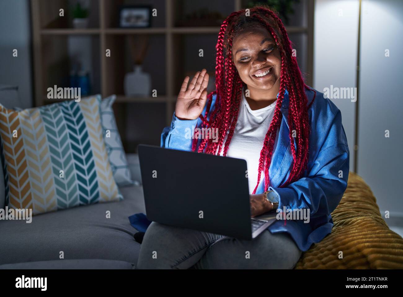 African american woman with braided hair using computer laptop at night ...