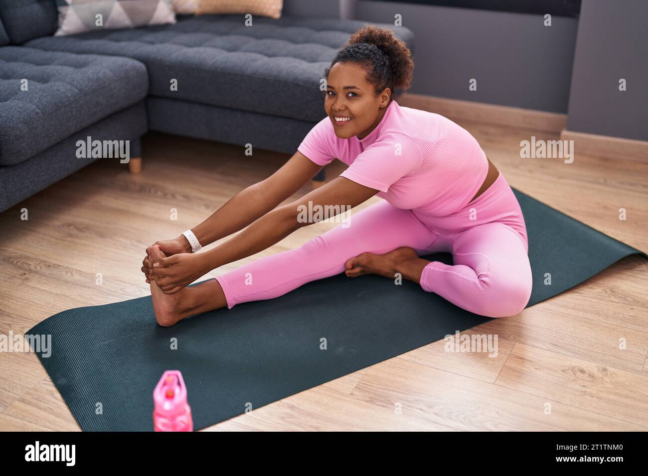 African american woman smiling confident stretching leg at home Stock ...