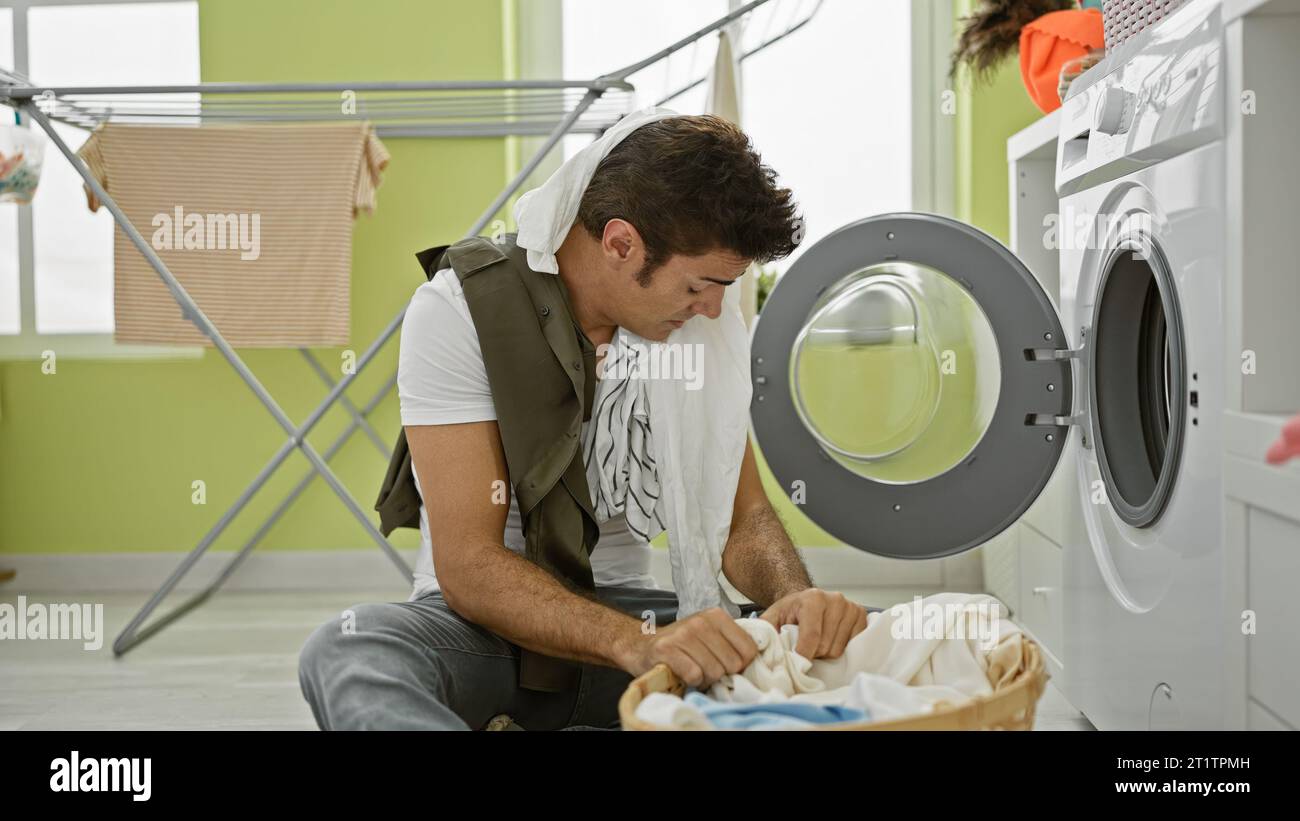 Young hispanic man washing clothes looking upset at laundry room Stock ...