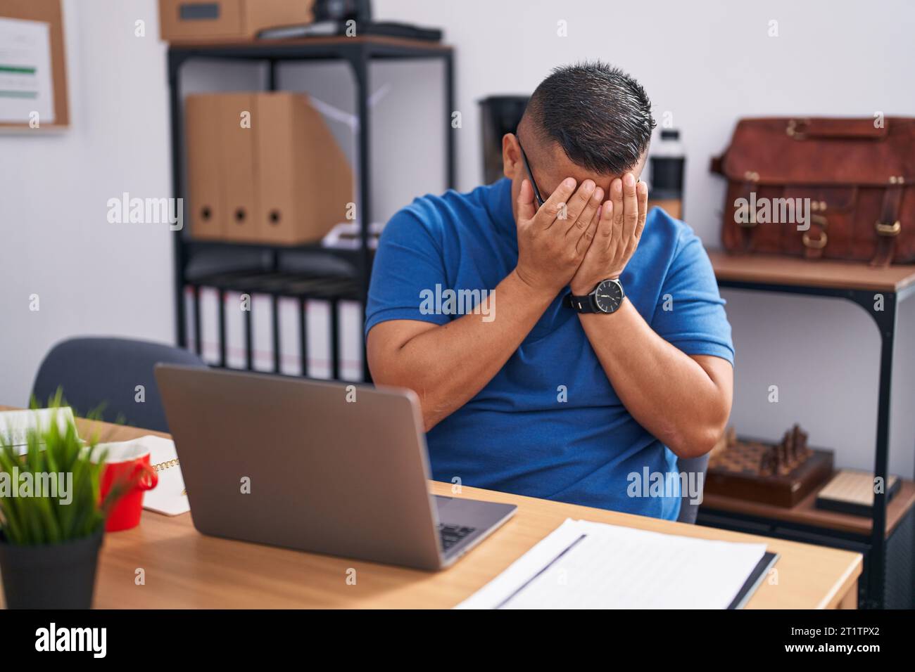 Young hispanic man working at the office with laptop with sad ...