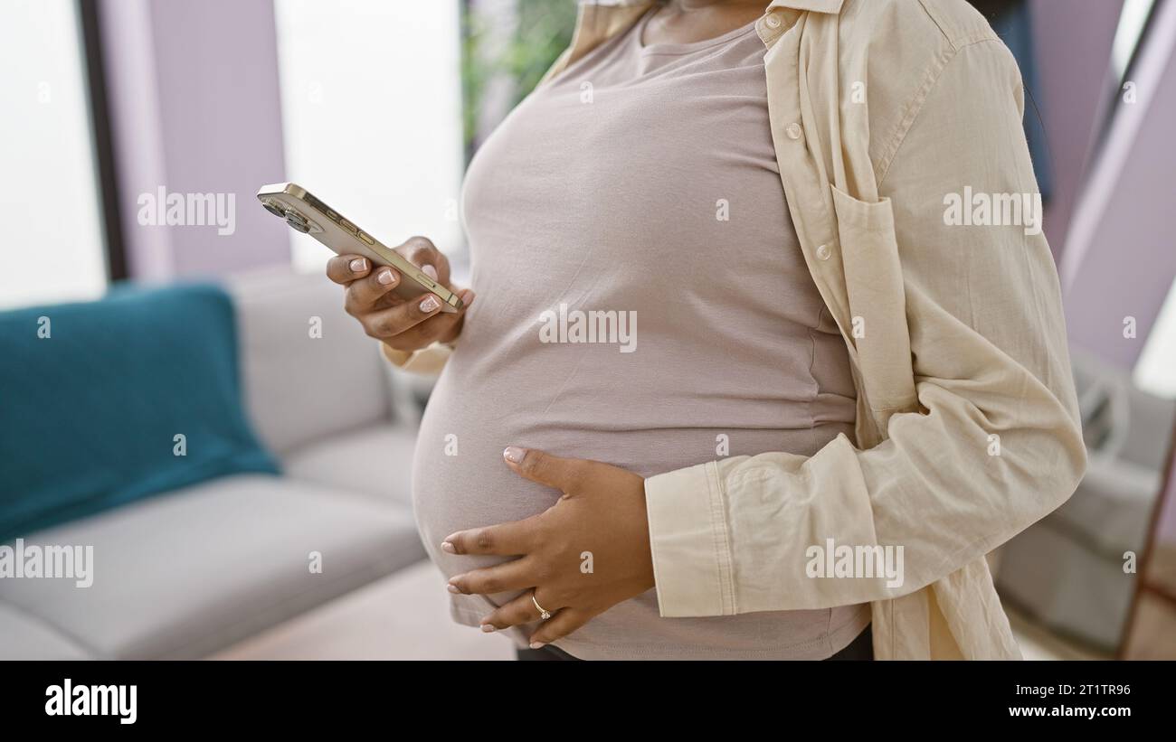 Young, casually successful hispanic woman touching her pregnant belly ...