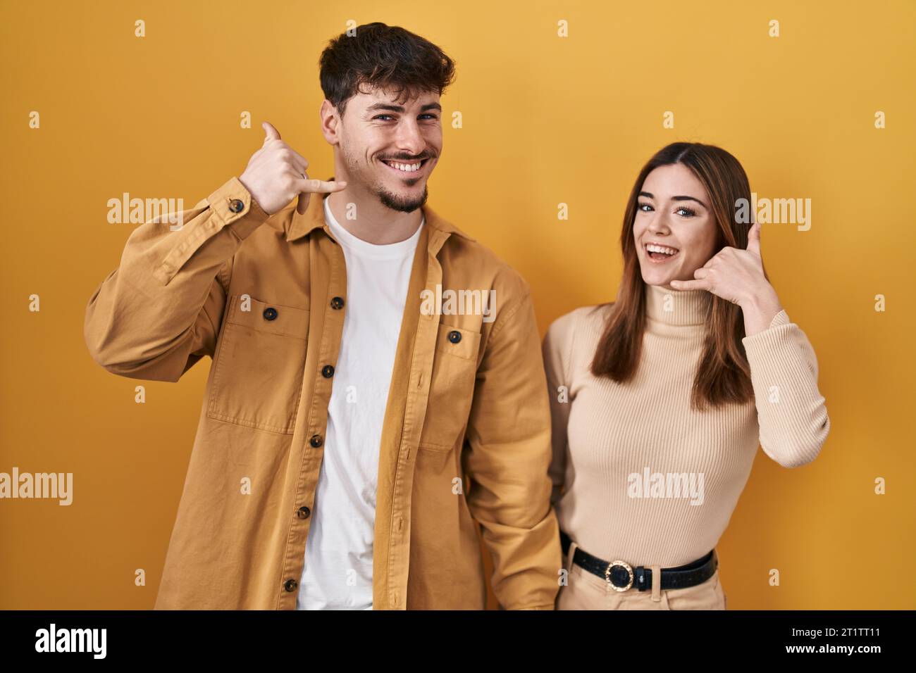 Young hispanic couple standing over yellow background smiling doing ...