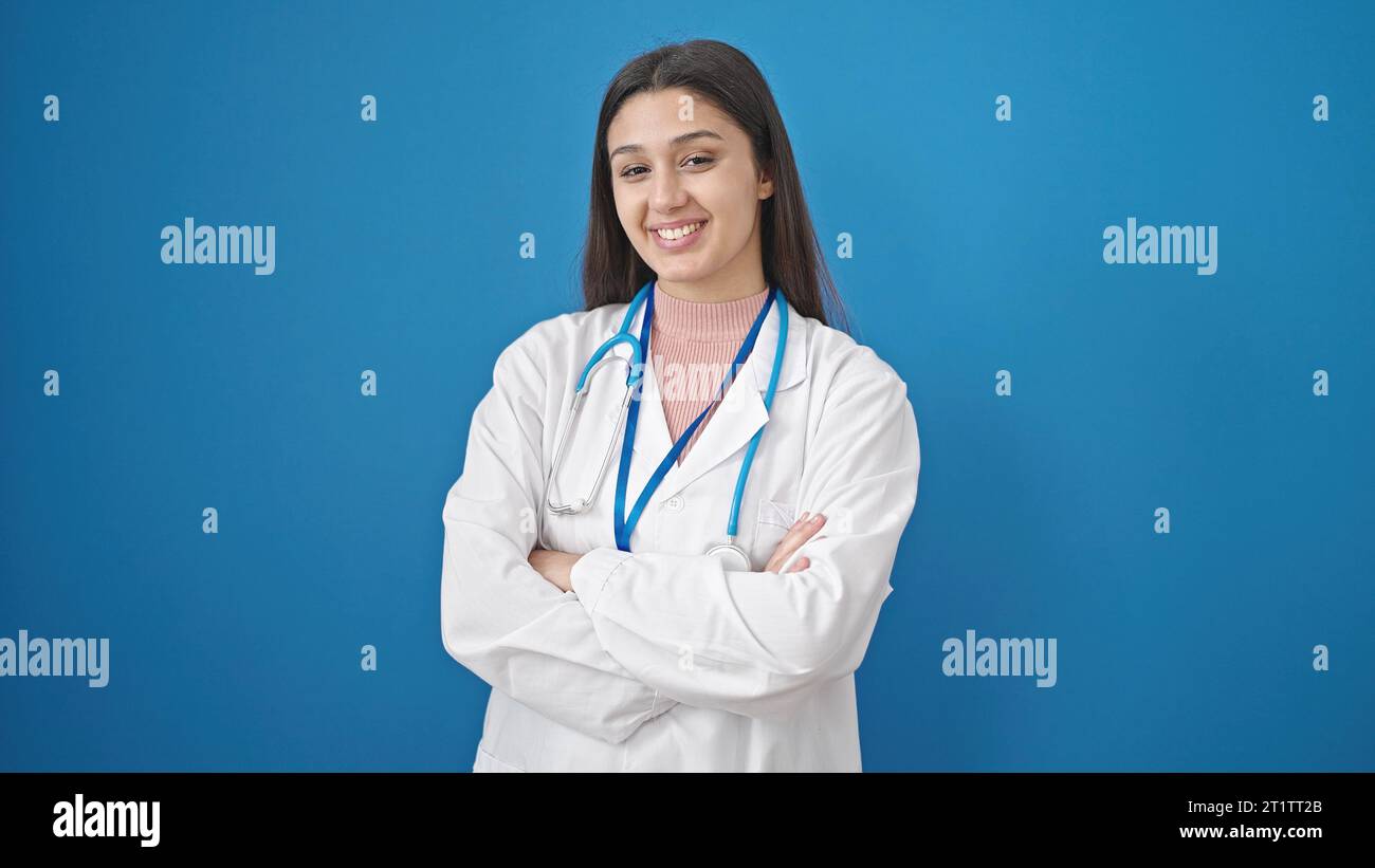 Young beautiful hispanic woman doctor standing with arms crossed ...