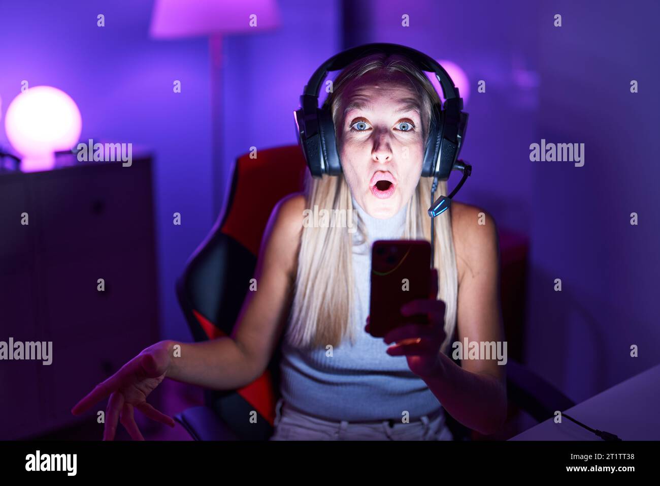 Young caucasian woman playing video games with smartphone scared and ...