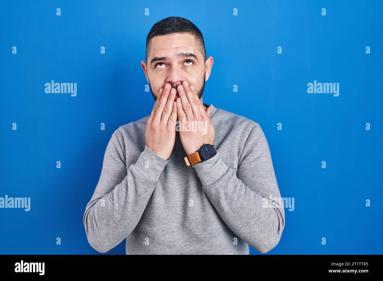 Hispanic man standing over blue background laughing and embarrassed ...