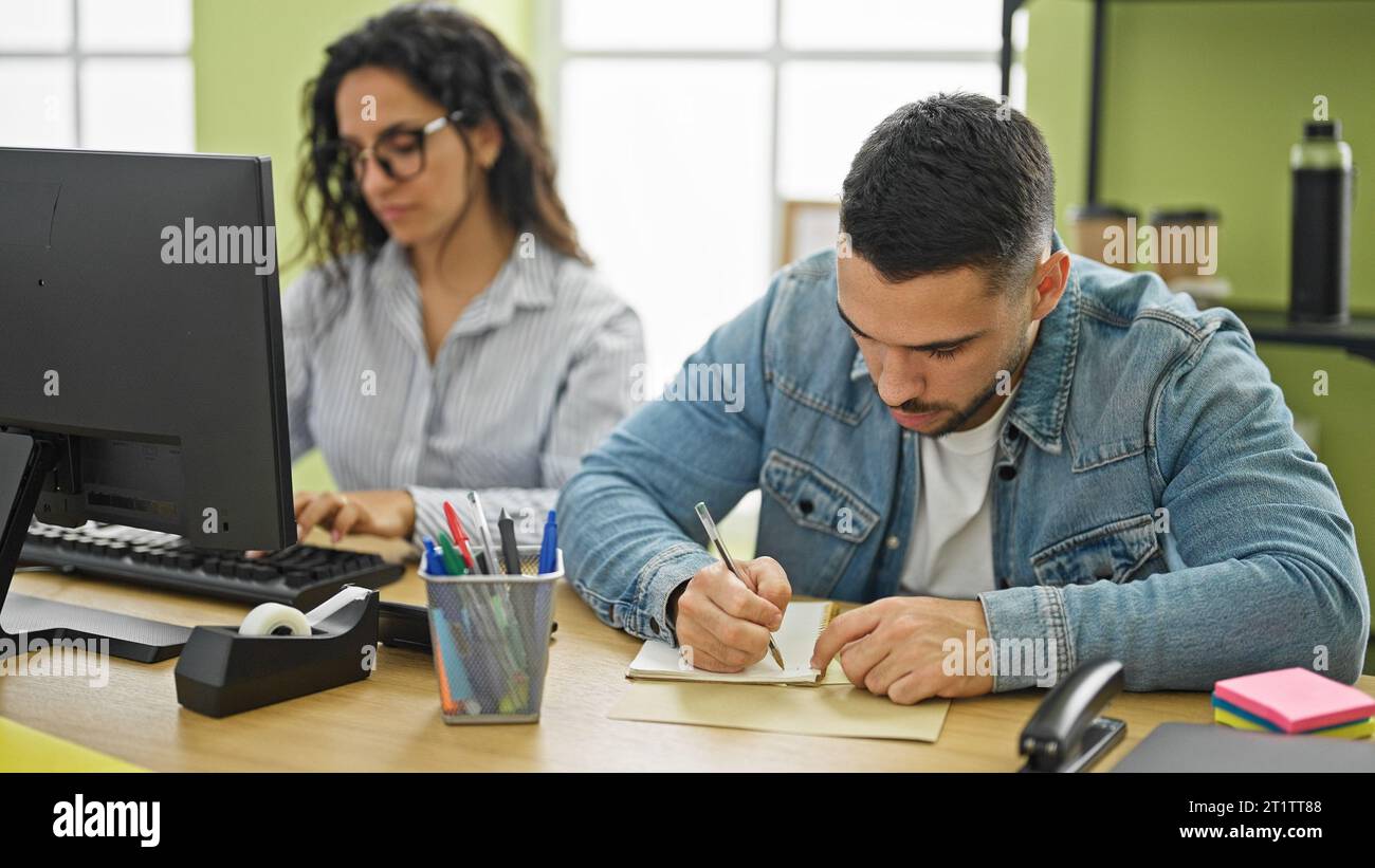 Man and woman business workers using computer taking notes at the ...