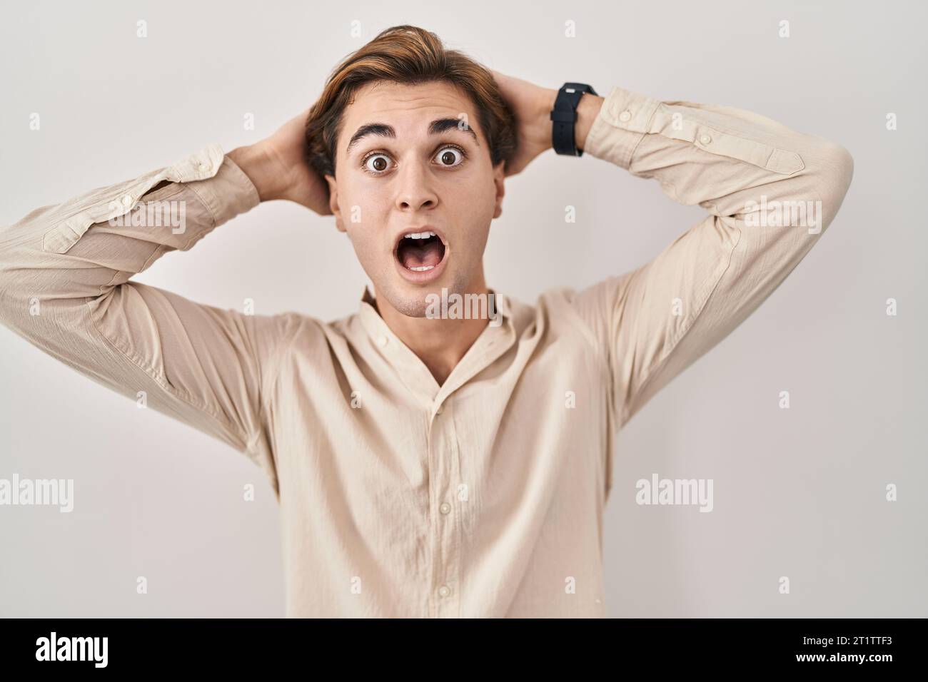 Young man standing over isolated background crazy and scared with hands ...