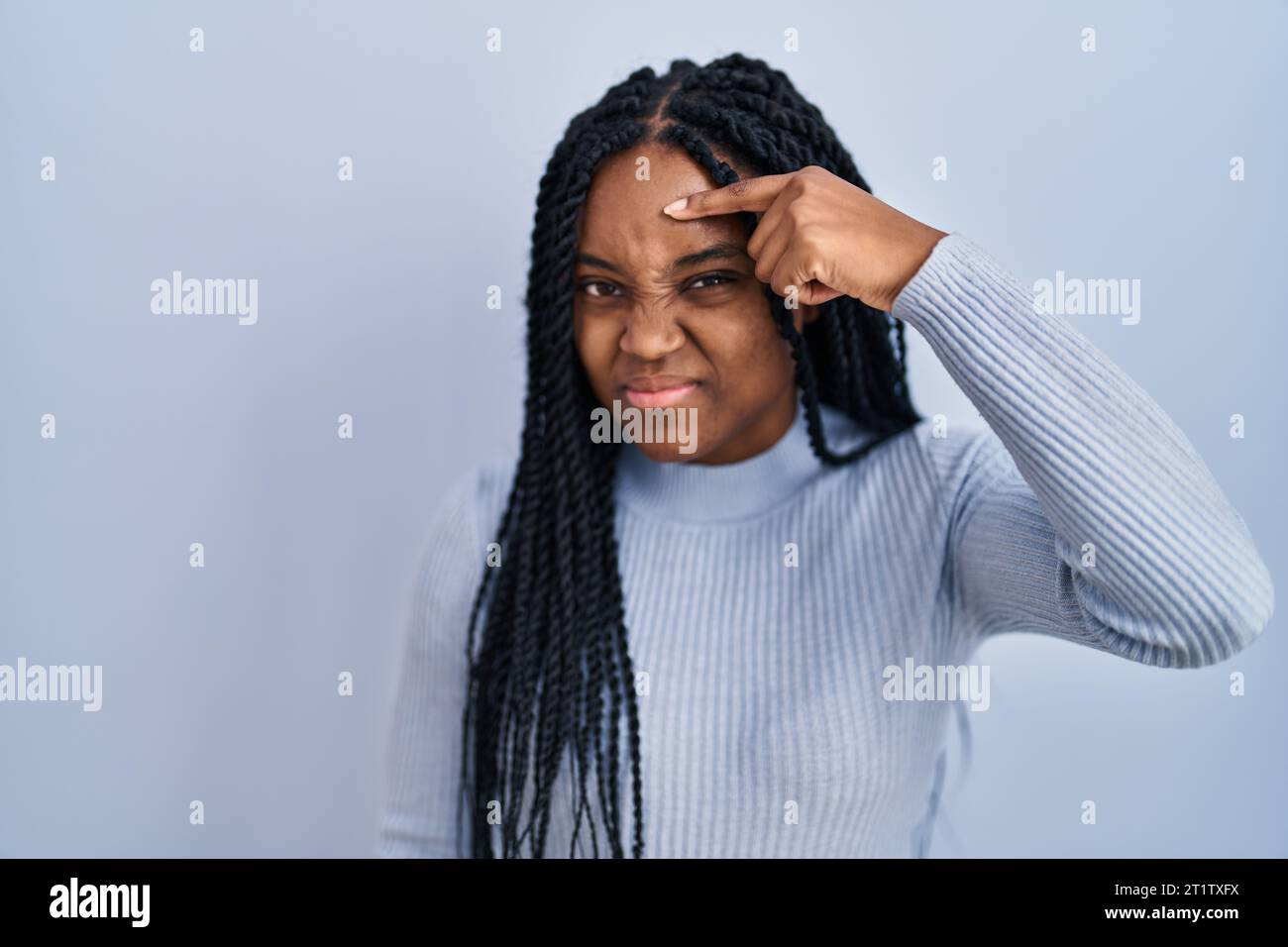 African american woman standing over blue background pointing unhappy ...