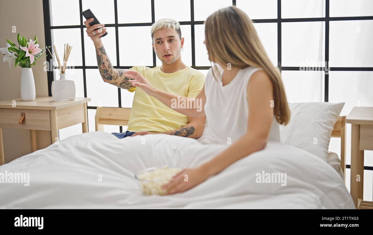 Beautiful couple watching tv fighting for remote control at bedroom ...