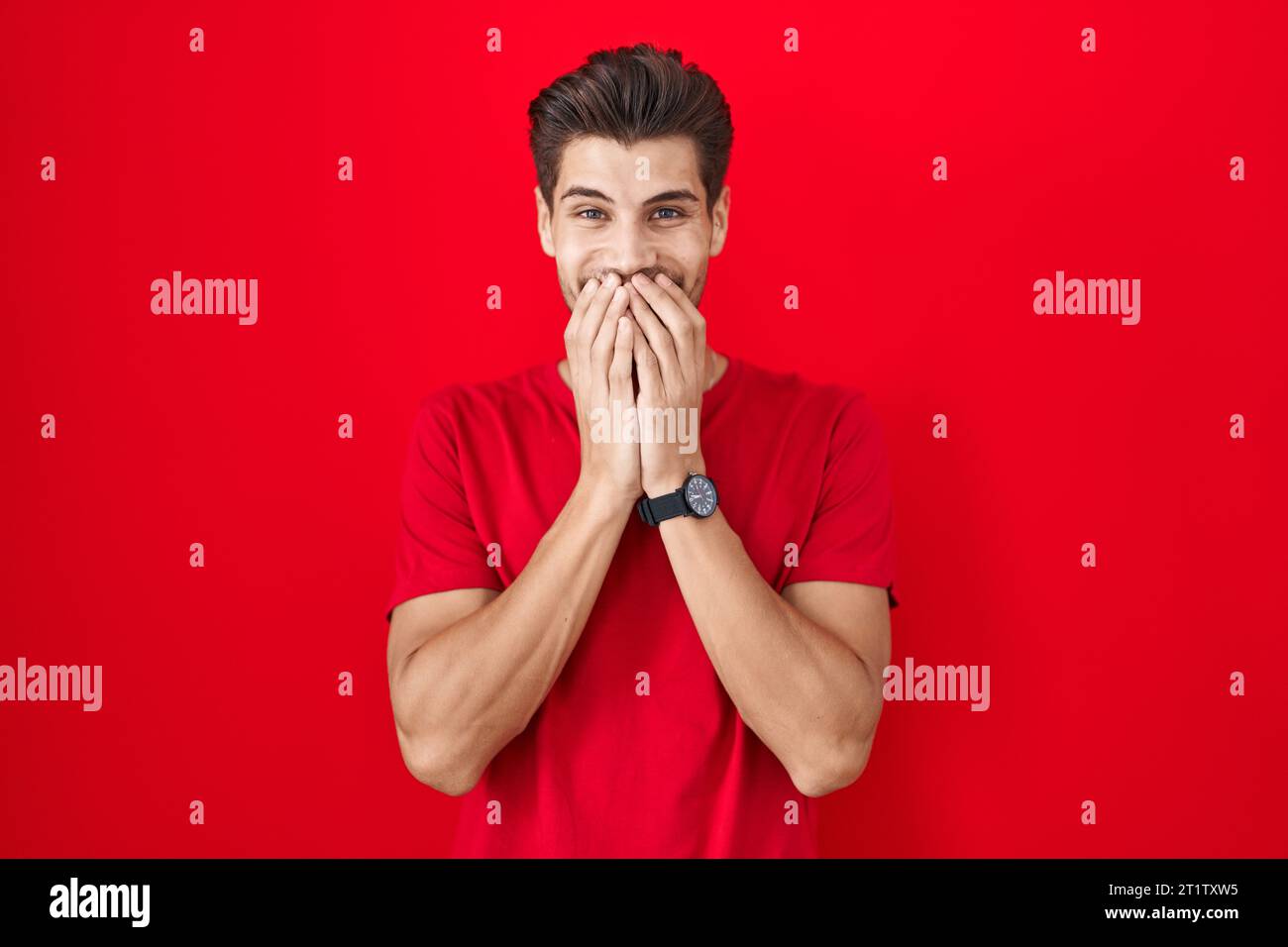 Young hispanic man standing over red background laughing and ...