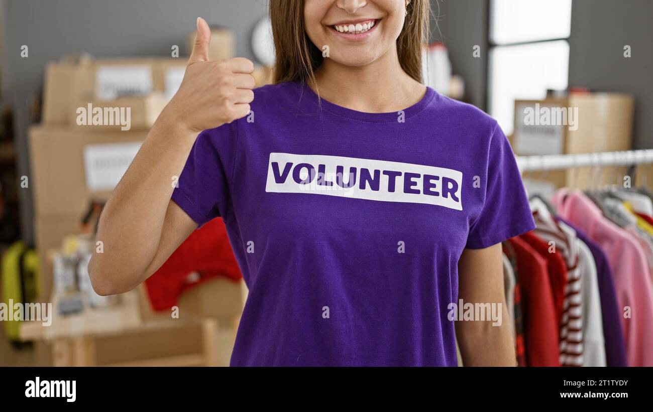 Beautiful young hispanic woman proudly volunteering at a charity center ...