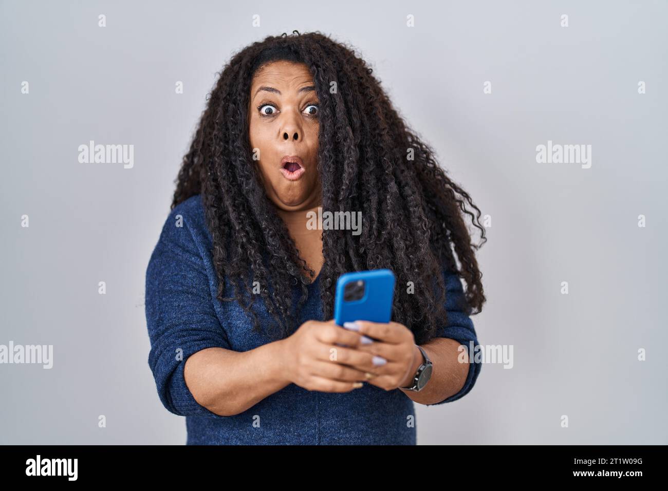 Plus size hispanic woman using smartphone typing message afraid and ...