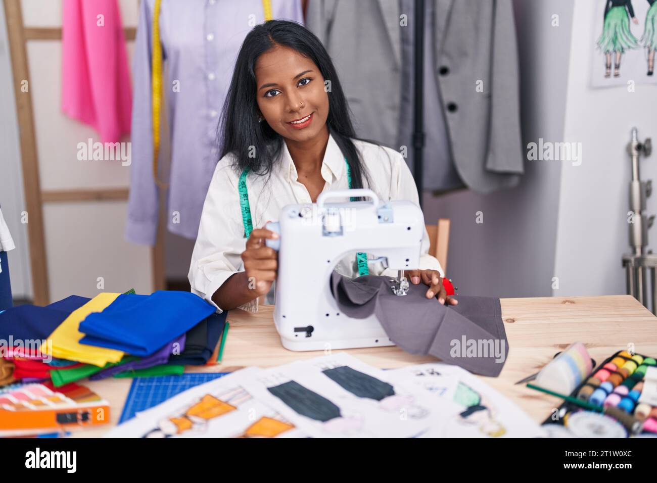 Young beautiful woman tailor smiling confident using sewing machine at ...