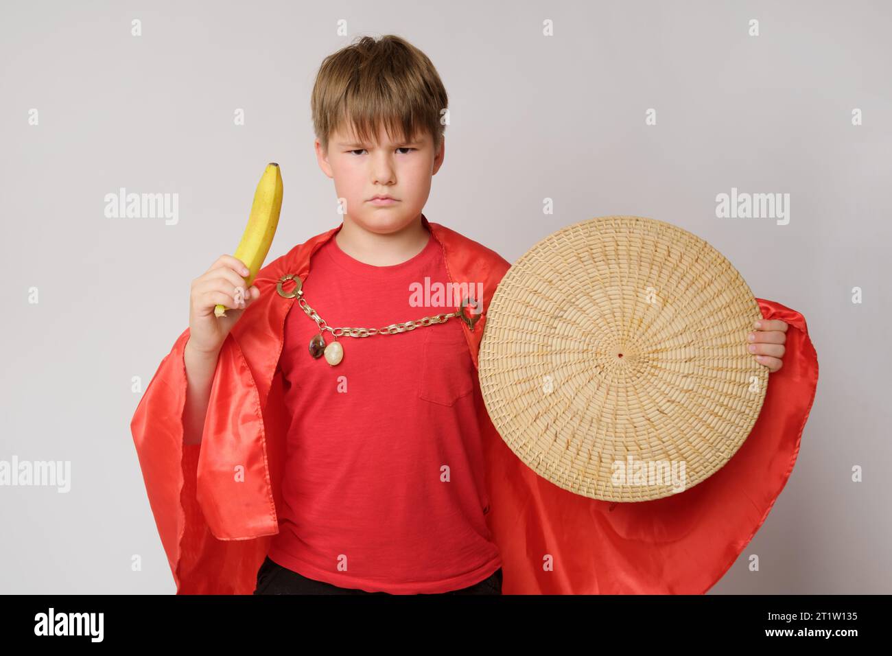 Funny child boy in a medieval knight costume. Boy in a red shirt and a ...