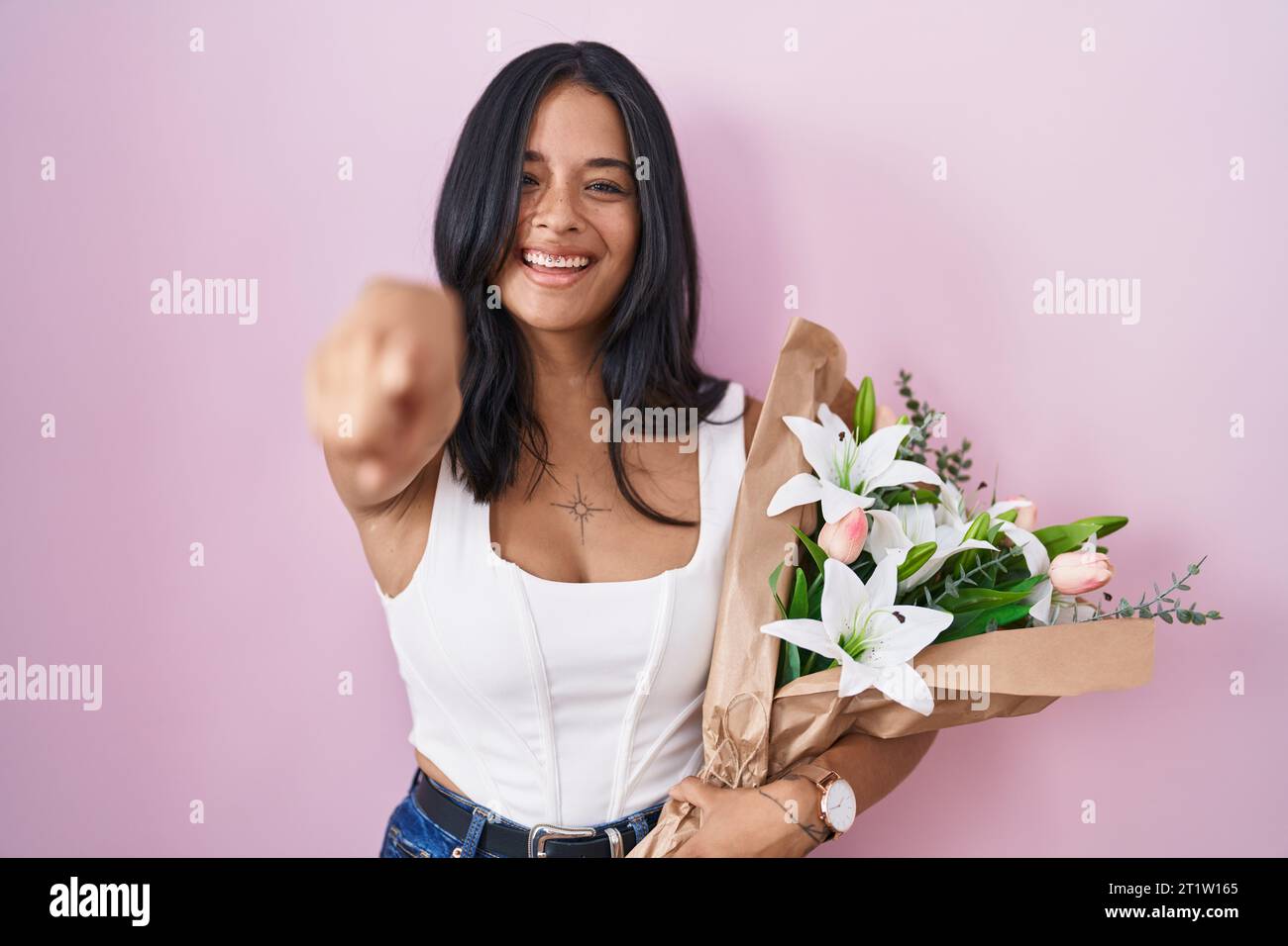 Brunette woman holding bouquet of white flowers pointing to you and the ...