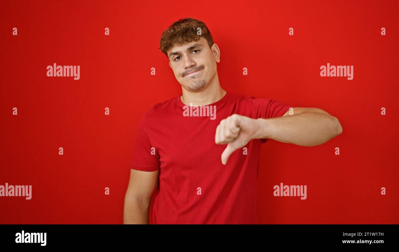 Cool hispanic youngster's negative signal, thumb down gesture, over red ...