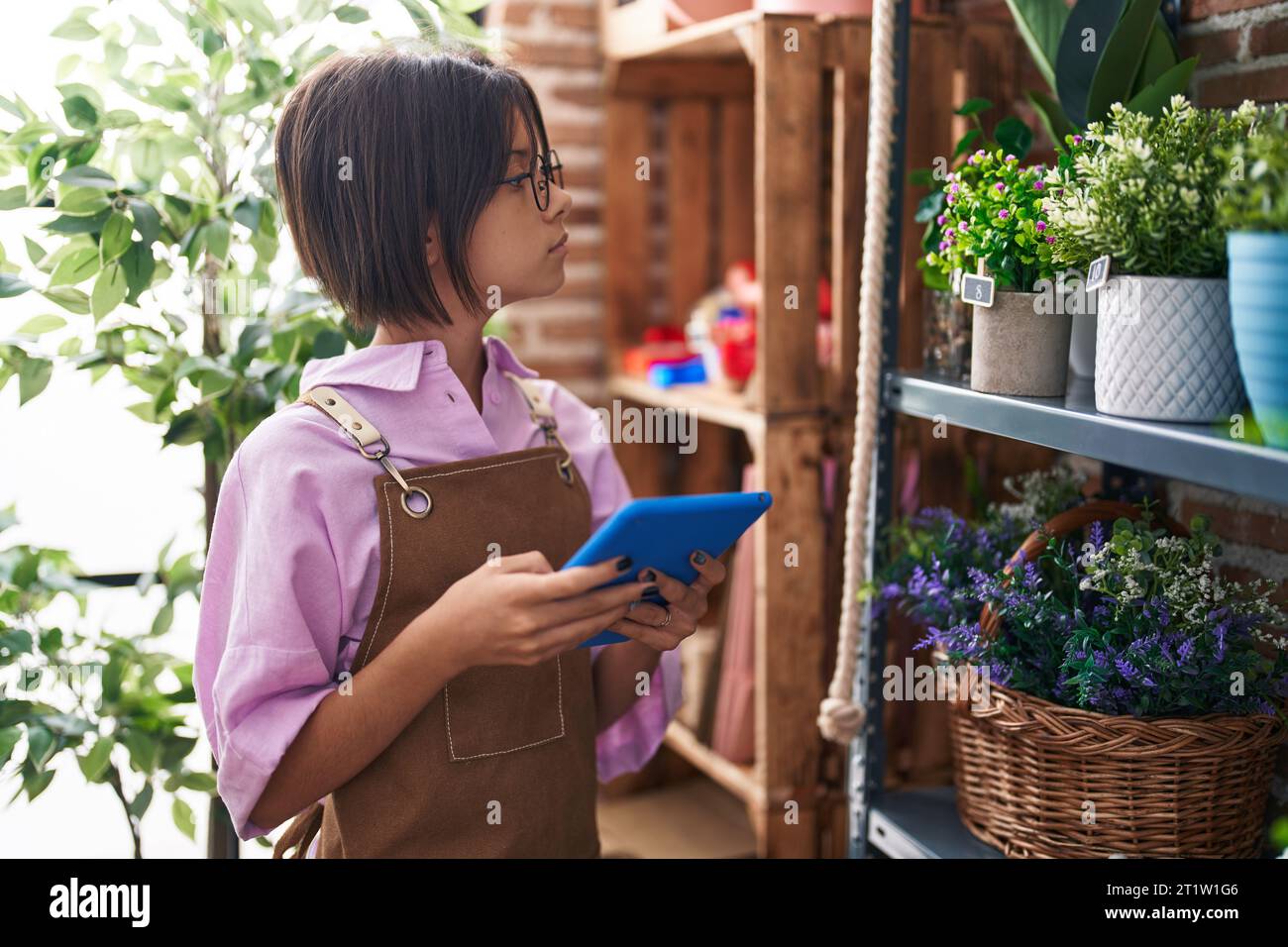 Adorable hispanic girl florist using touchpad at flower shop Stock ...