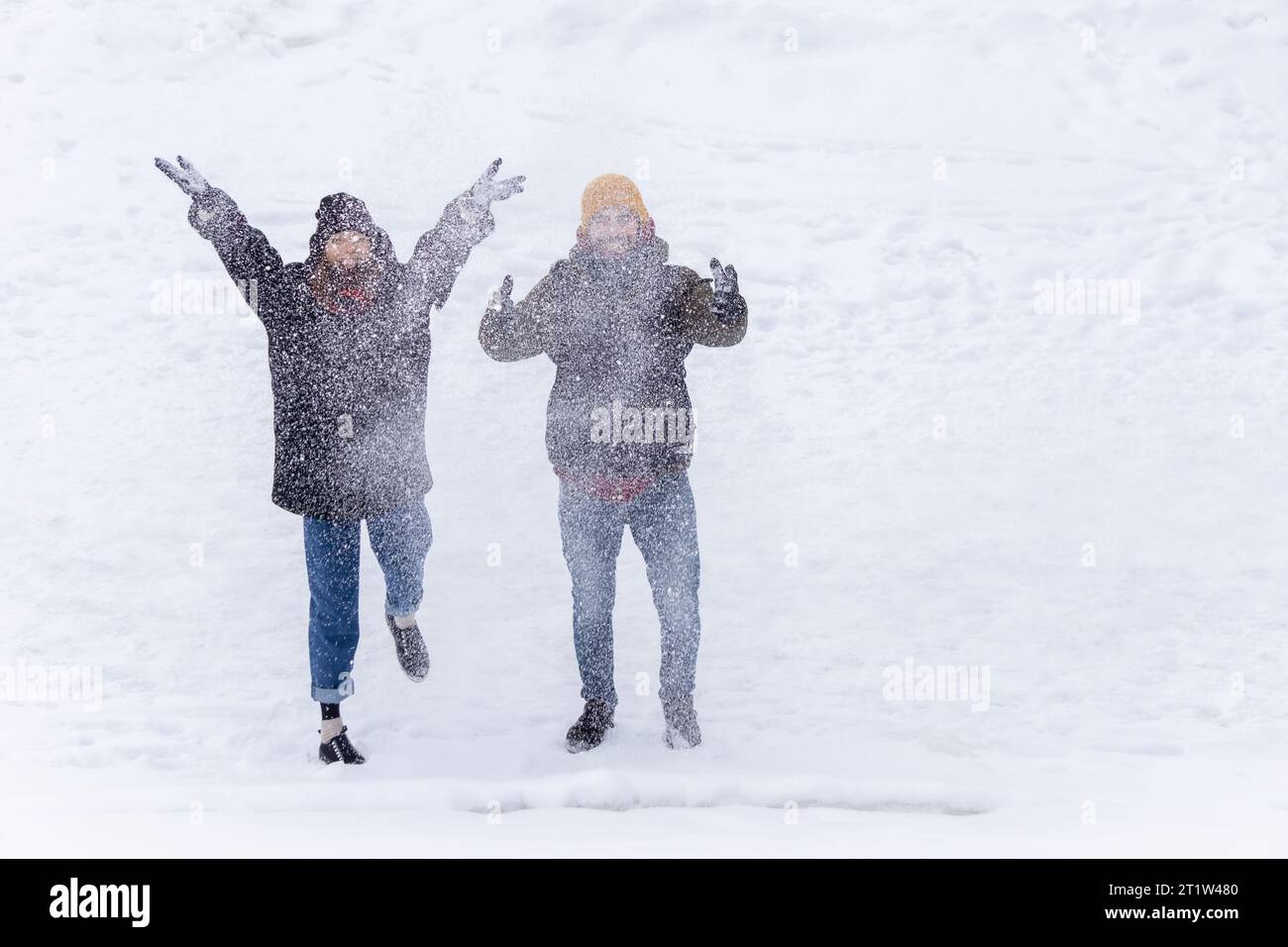 Couple throwing snow and enjoying winter time in field, full of snow ...