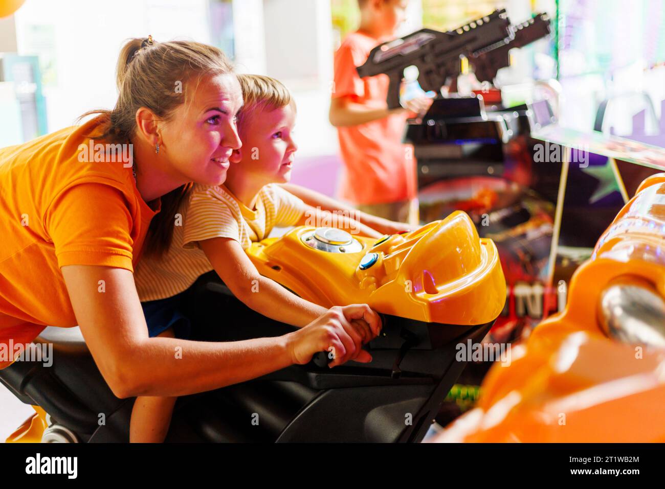 Mother and son play in an arcade motorcycle simulator in an ...