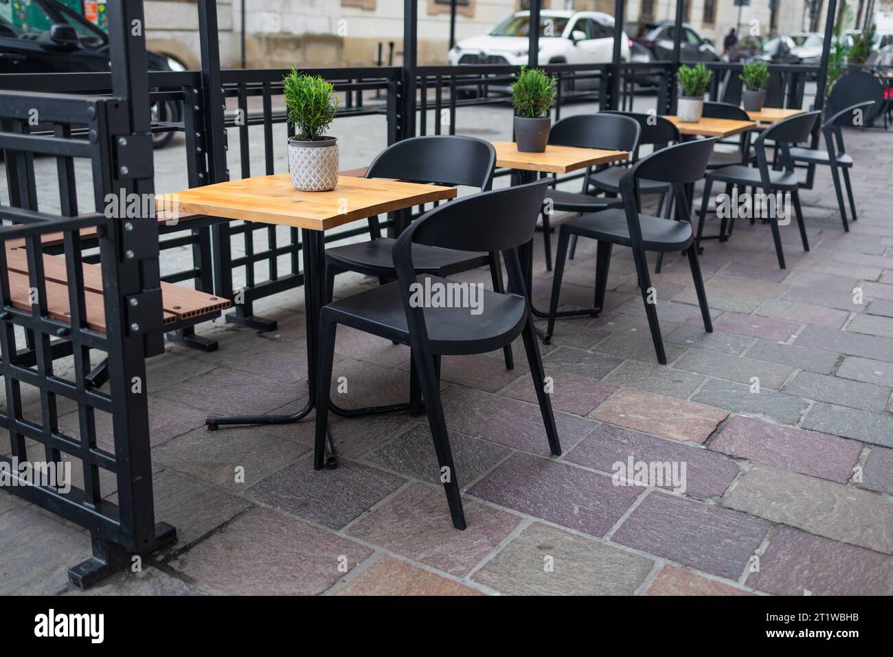 Modern street cafe with wooden tables with chairs standing next to them ...