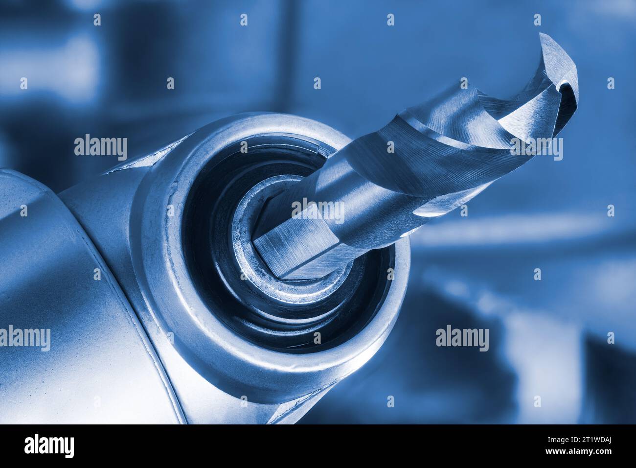 Sharp drill bit clamped in machine chuck with right angle head in blue ...