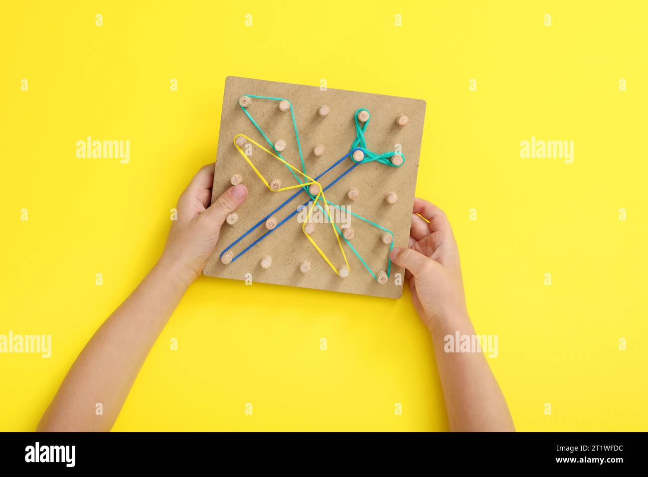 Motor skills development. Boy with geoboard and rubber bands at yellow ...