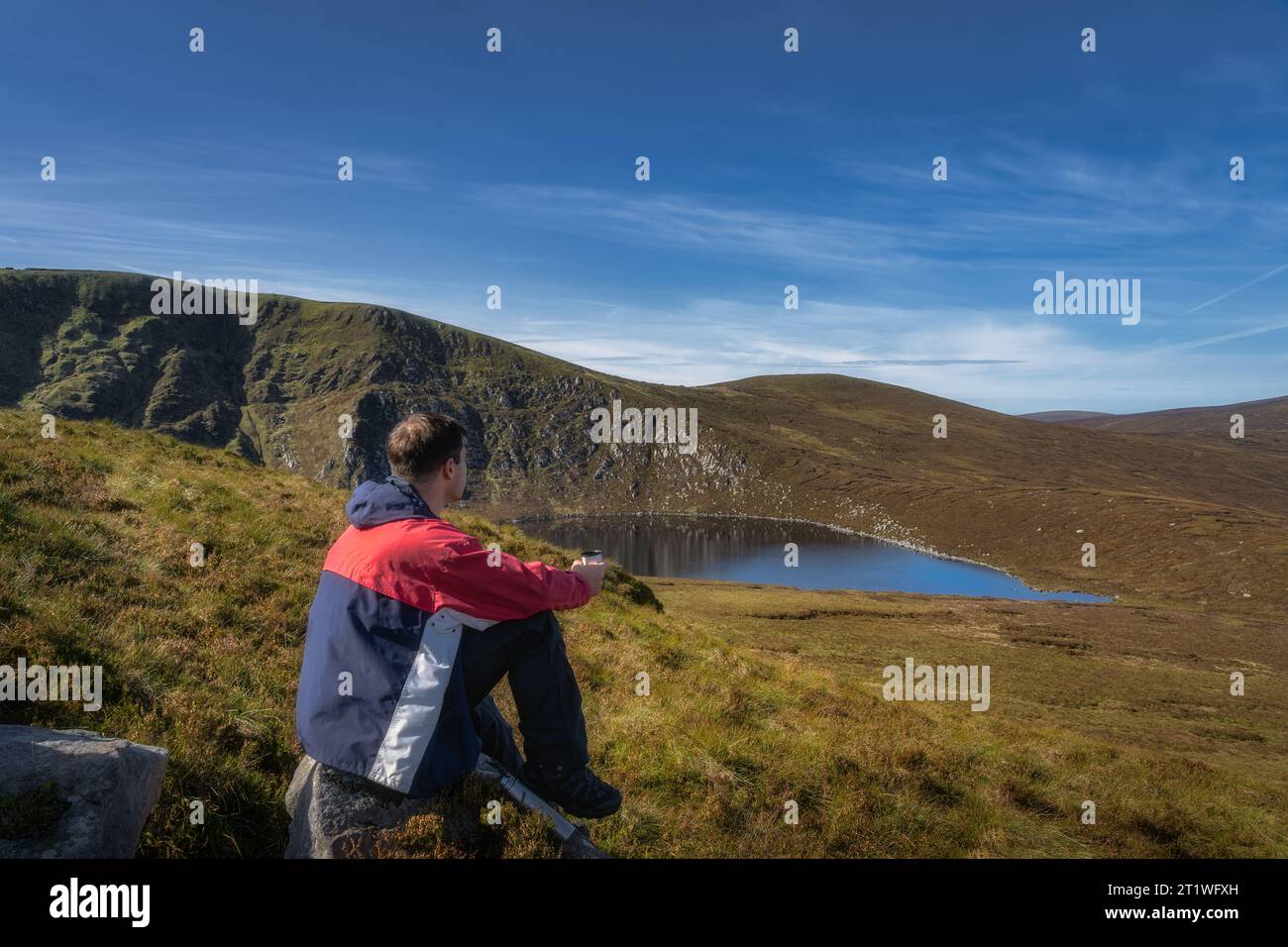 Men sitting on a rock and drinking coffee or tea from thermos. Scenic ...