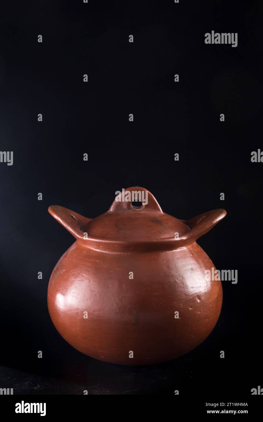 front view of a clay pot, with its lid; everything is red and we have ...