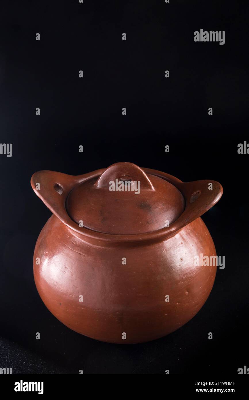front view of a clay pot, with its lid; everything is red and we have ...