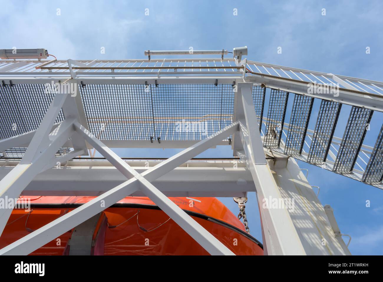 red, orange lifeboat hanging on a ferry in front of blue sky Stock ...