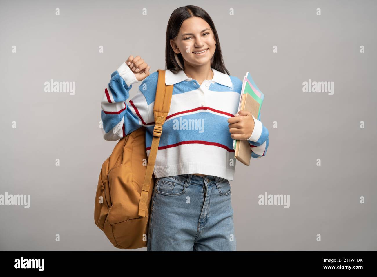 Positive student teen school girl rejoice on grey studio blank with ...