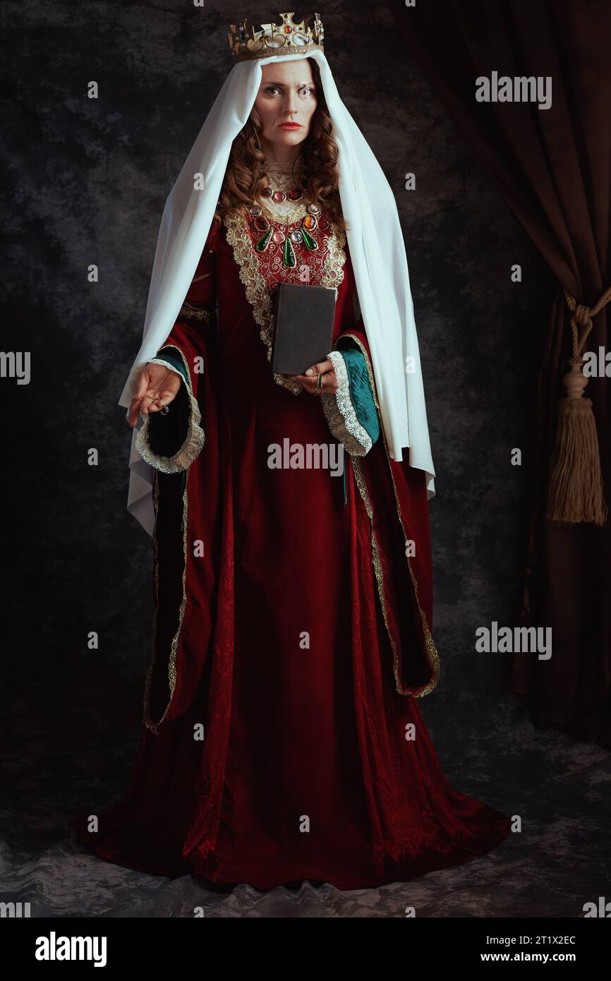 Full length portrait of medieval queen in red dress with book, veil and ...