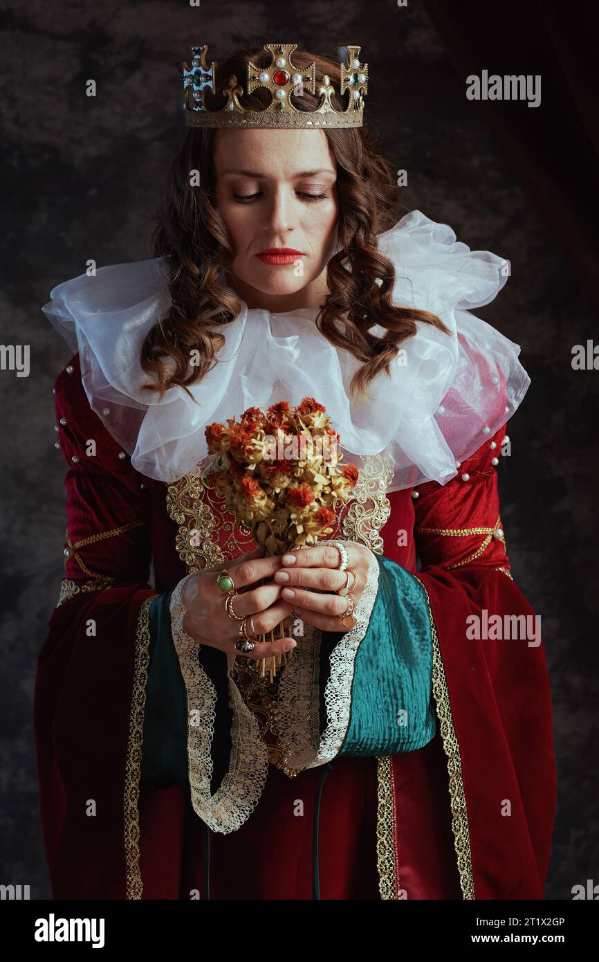 medieval queen in red dress with dried flower, white collar and crown ...