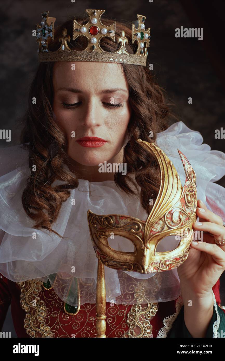 medieval queen in red dress with venetian mask, white collar and crown ...